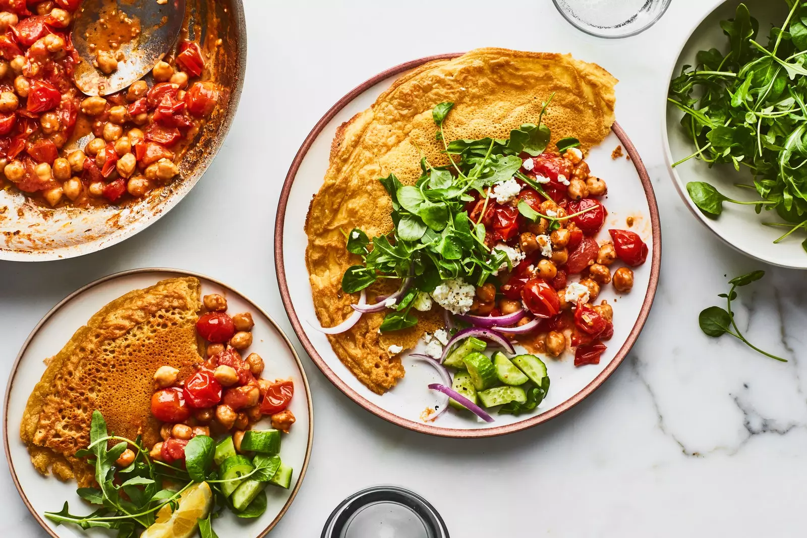 Roti buncis berbahan dasar minyak zaitun yang dibagikan di antara dua piring dengan saus tomat dan baby greens.