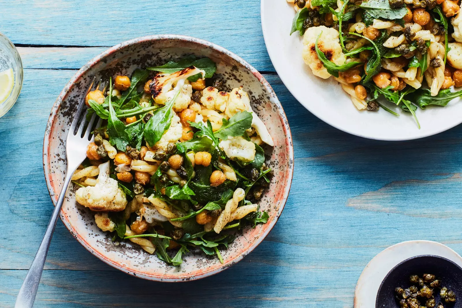 Deux bols de pâtes aux pois chiches, chou-fleur et roquette.