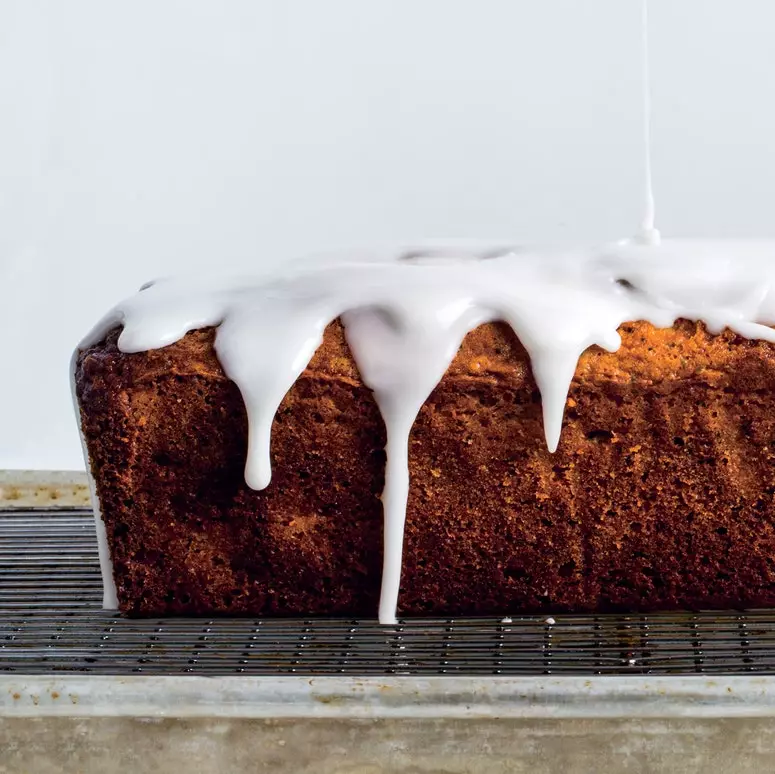 Sidevisning av grapefruktvalmue-brødkake som er toppet med dryppende hvit yoghurtglasur.