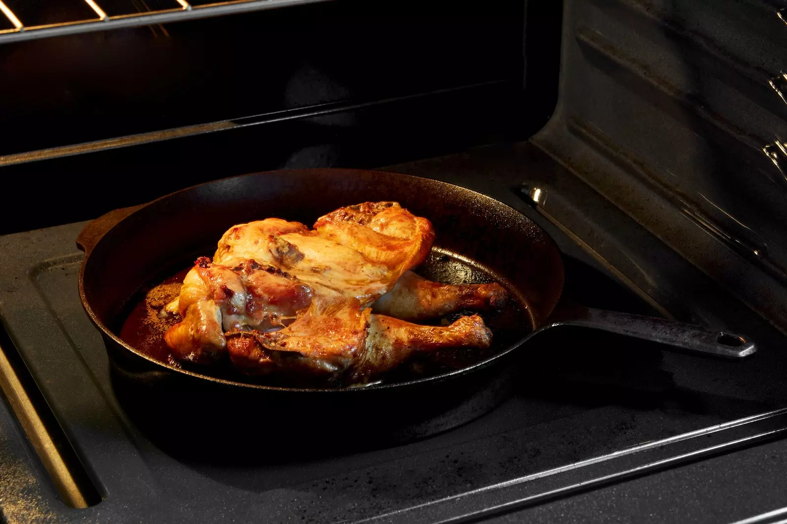 Foto van een hele kip roosteren in een oven.