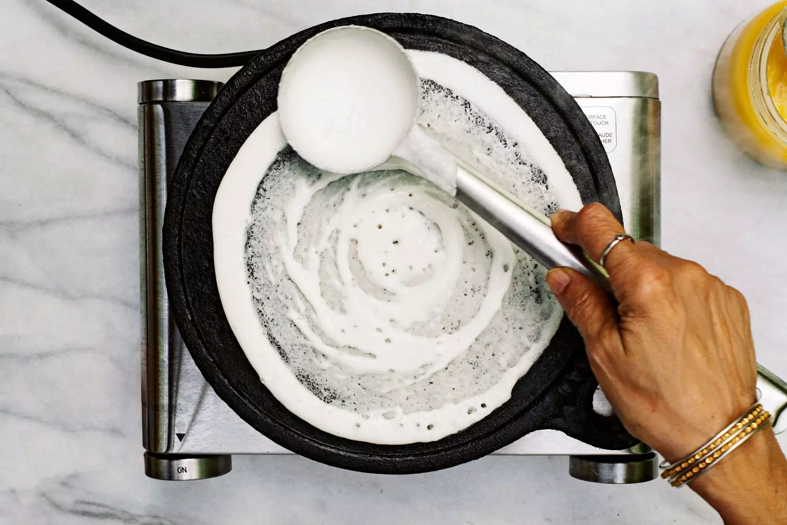 Foto da massa dosa sendo espalhada em uma chapa quente.