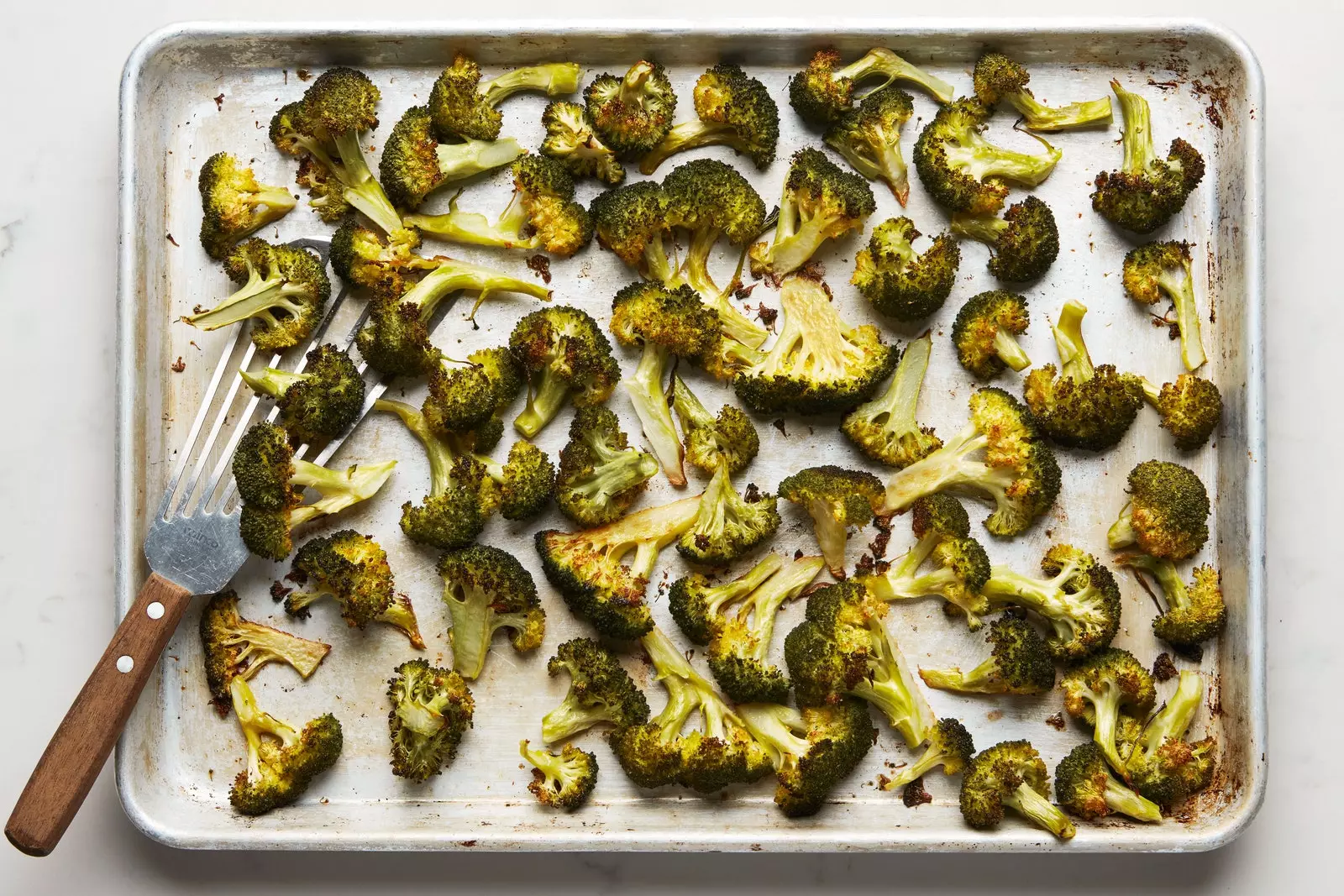 Zdjęcie pieczonych brokułów na blasze do pieczenia z łopatką.