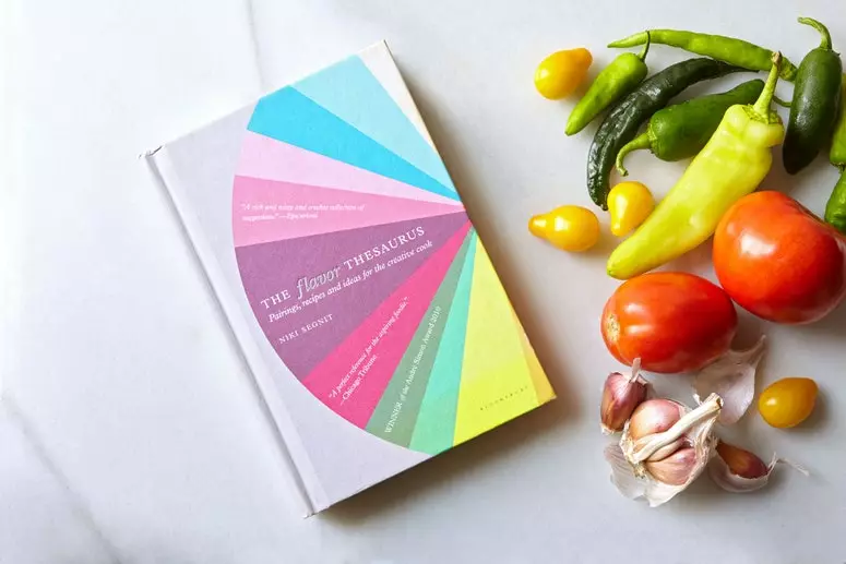 Foto des Buches „The Flavour Thesaurus“ von Niki Segnit auf einer Marmorplatte mit Paprika, Tomaten und Knoblauch.
