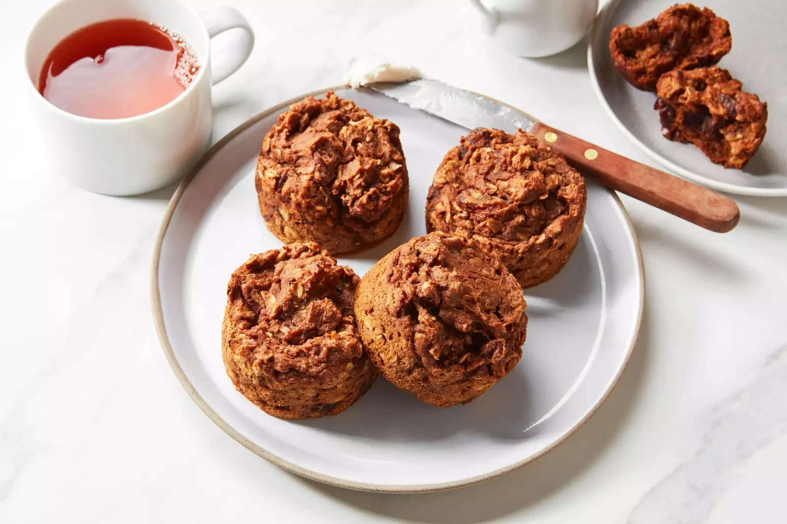 Awo ti Dun Ọdunkun Ọjọ Muffins pẹlu kan ago tii lori ẹgbẹ.