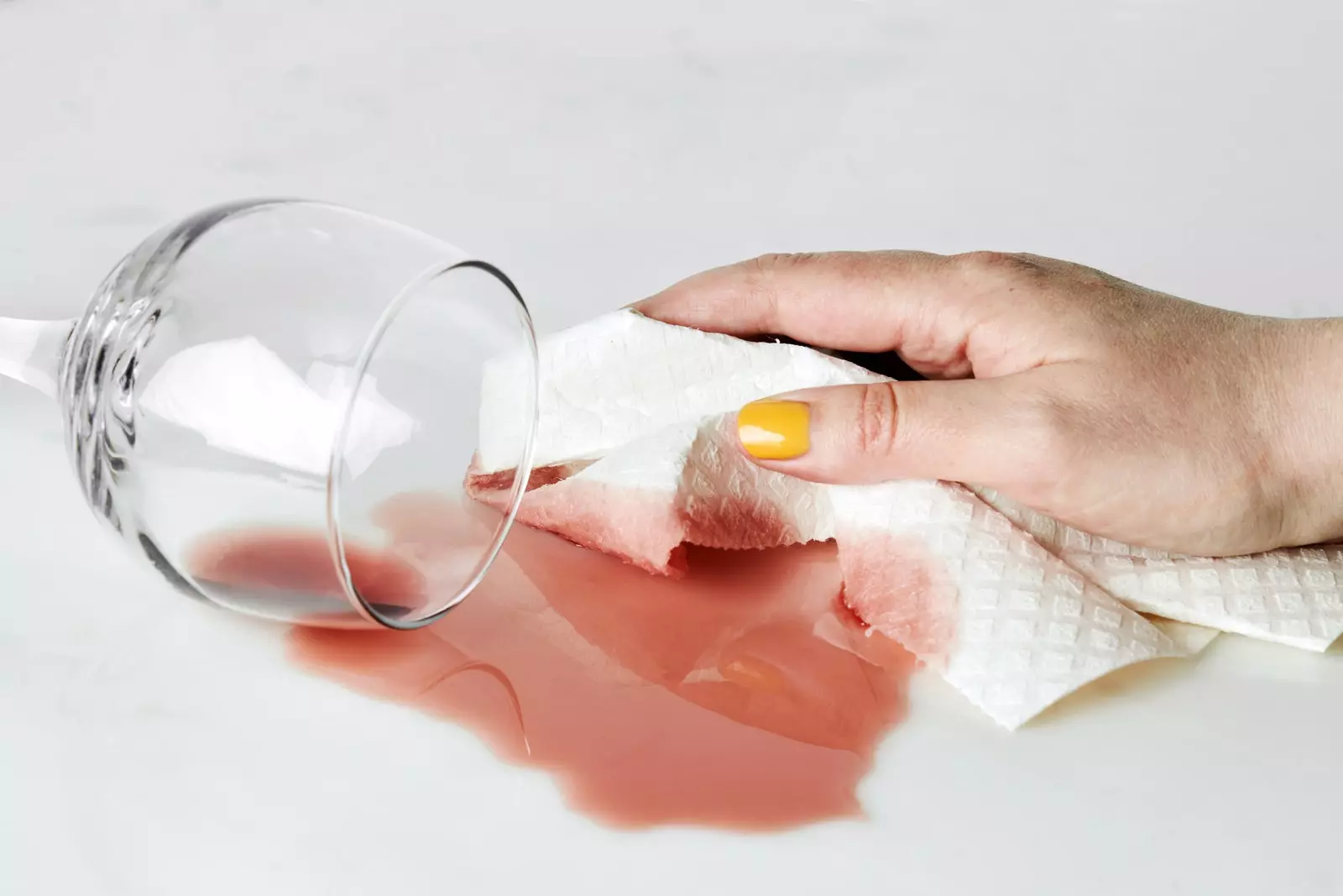 תמונה של מישהו שמשתמש במגבת נייר לשימוש חוזר כדי לנגב יין שנשפך.