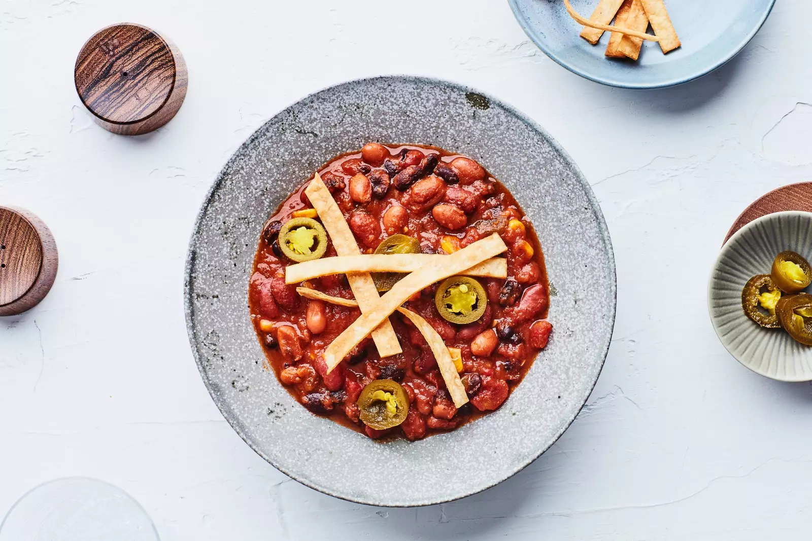 Foto vun engem Threebean Chili an enger flächeger groer Schossel dropgesat mat Tortilla Sträifen.