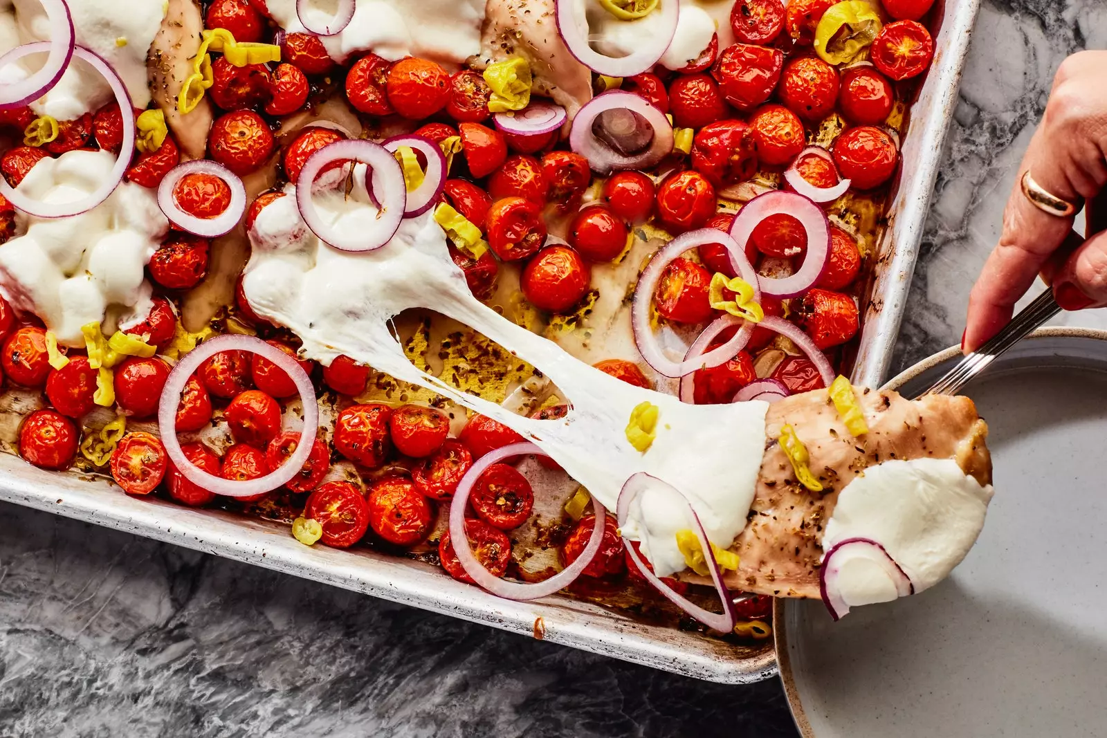 Foto lehtpannil röstitud ja taldrikule serveeritud tomatite juustust ja sibulast.