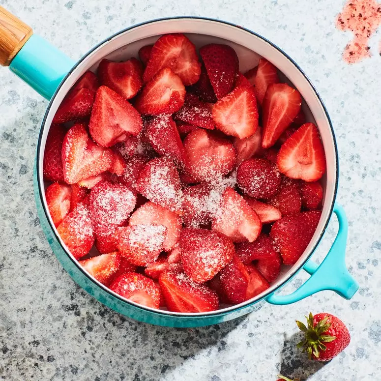 草莓食谱 绿松石平底锅中大批量草莓蜜饯配料的照片。