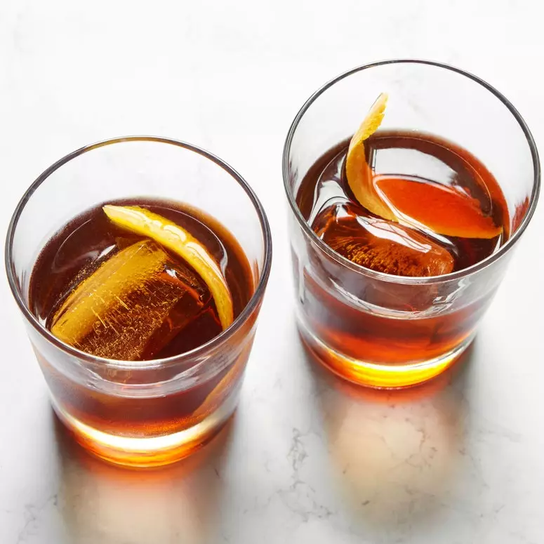 Foto no divām glāzēm kokteiļa 'Atceries alimentus' ar apelsīnu piedevām.
