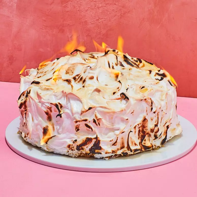 Kue bunder sing ditutupi karo meringue panggang kanthi nyala api saka ndhuwur ing latar mburi jambon.