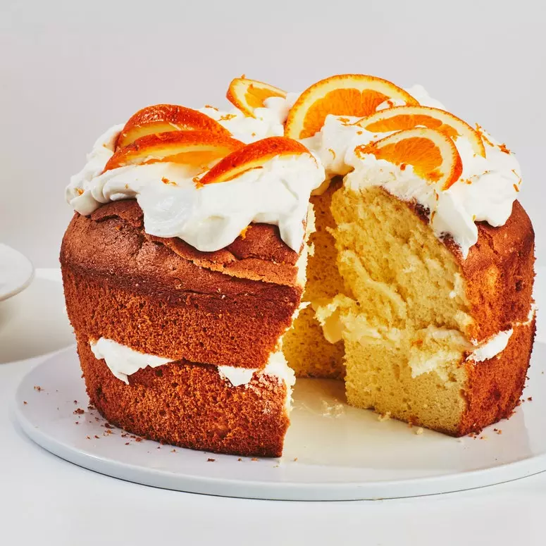 Orange Chiffon Cake sa usa ka serving platter nga adunay puti nga background.