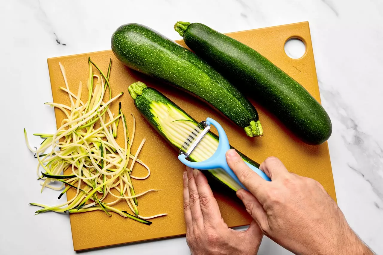 Un pelapatate tailandese con tre zucchine e tagliere.