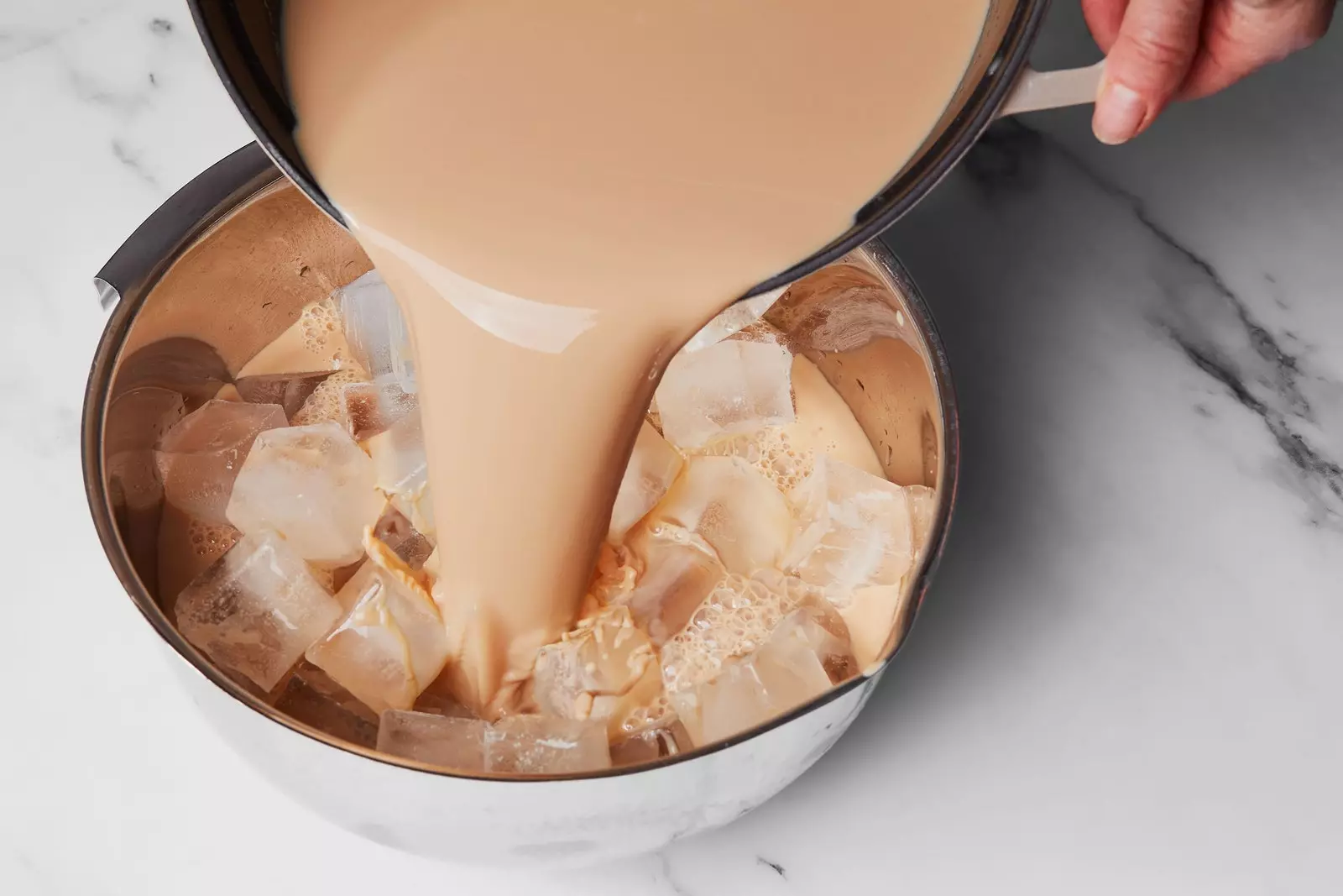 Foto de chai que se vierte en un recipiente con cubitos de hielo.