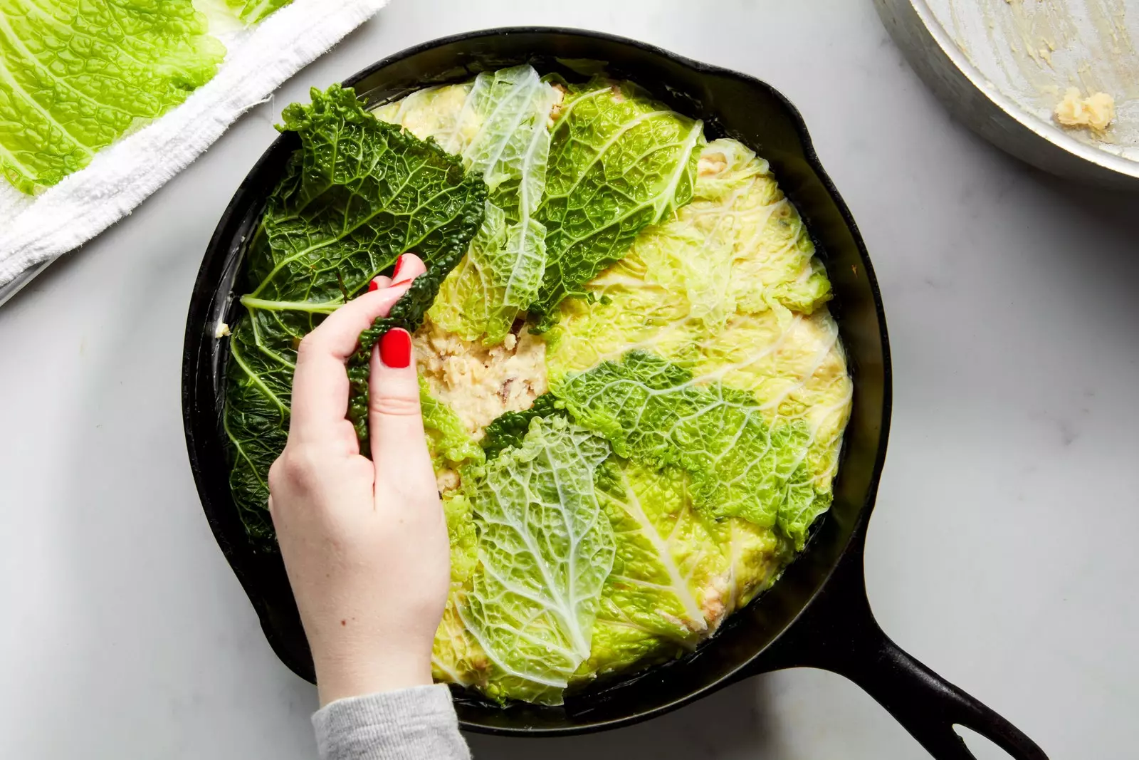 Ritratt ta 'persuna li tiwi weraq tal-kaboċċi biex jiffurmaw torta.