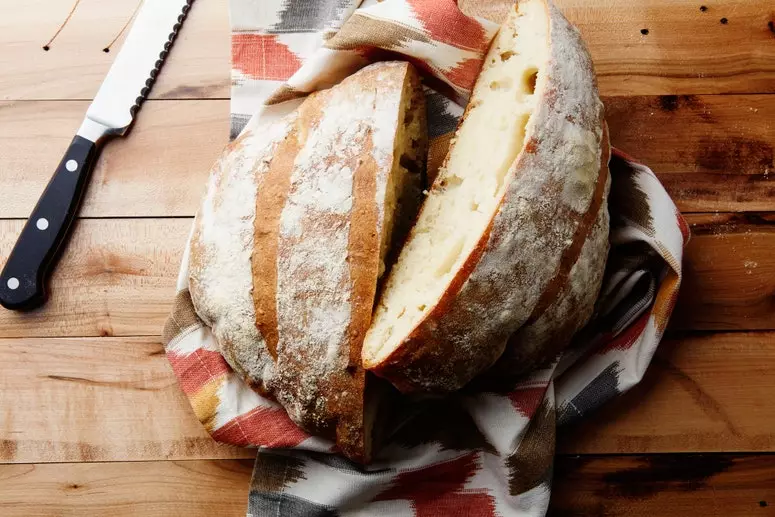 Bedste brødopskrifter: Foto af et hjemmebagt brød på et skærebræt, hvilket er mere miljøvenligt, da det ikke har nogen plastikemballage.