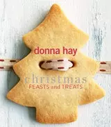 Foto de la portada del libro de cocina Christmas Feasts and Treats con una galleta con forma de árbol de Navidad sobre una superficie blanca.