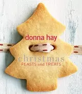 Foto van de kookboekomslag van Christmas Feasts and Treats met een koekje in de vorm van een kerstboom op een wit oppervlak.