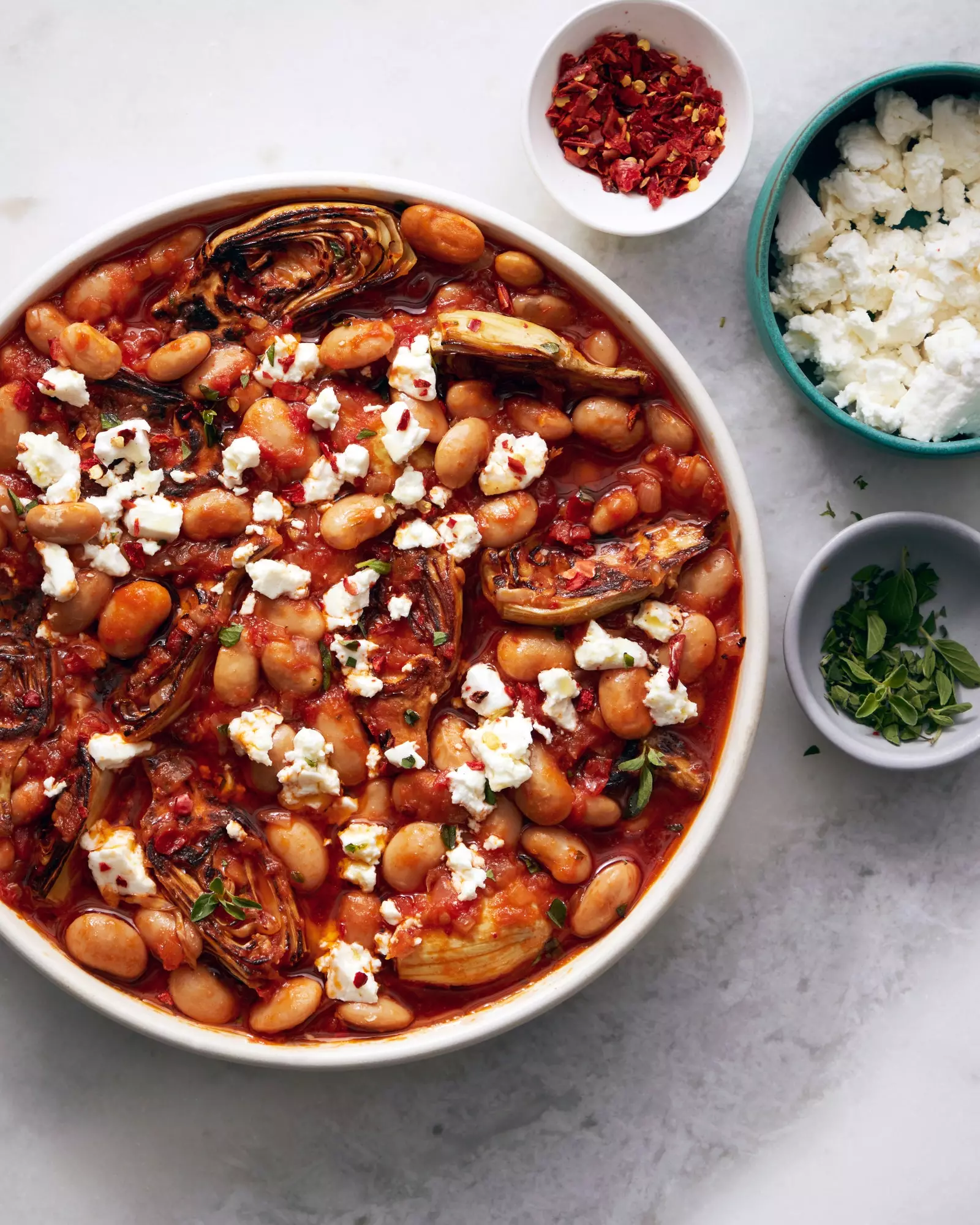 foto de xudías xigantes cocidas con tomate, alcachofas e feta