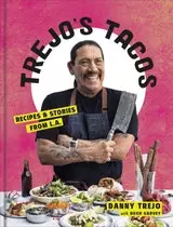 Trejo's Tacos тамак китебинин мукабасында Дэнни Трежонун сүрөтү менен тако толгон столдун алдында турат.