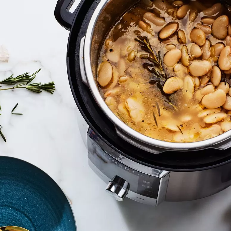 Frijoles blancos y hierbas en una olla instantánea.