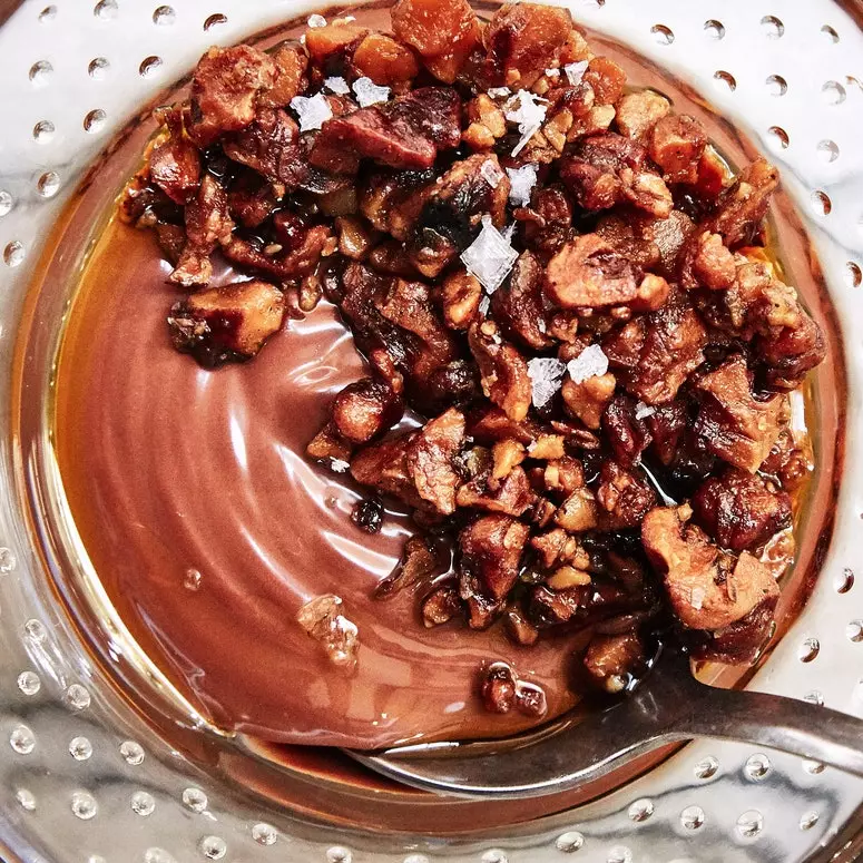 Glasskål fylld med chokladpudding och kanderade valnötter toppad med flingigt havssalt.