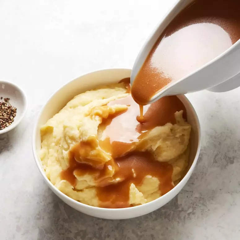 Glutenfreie Soße wird auf Kartoffelpüree gegossen.