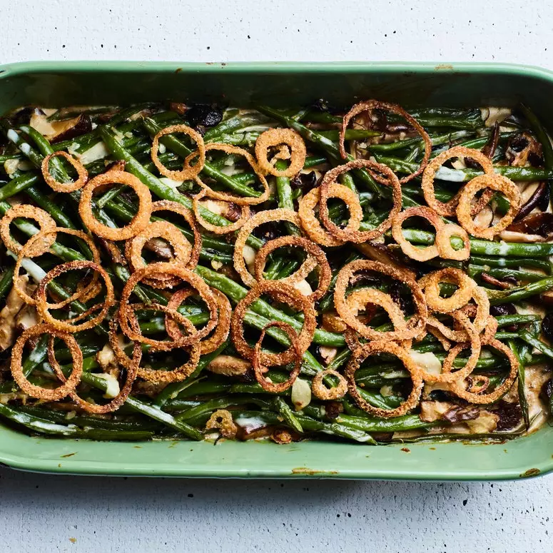 Casserole kacang hijau dan jamur dalam piring persegi panjang hijau dengan pegangan.