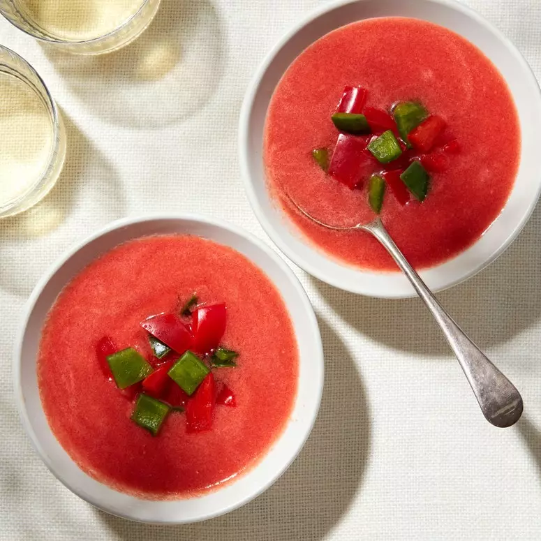 Duas taças de Gaspacho Andaluz com duas taças de vinho branco ao lado.